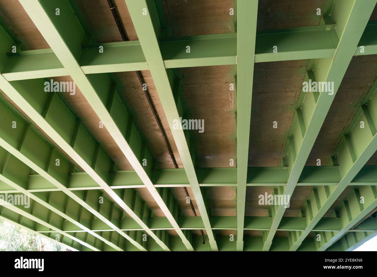 Underneath view of a green-painted bridge, showing the structure's ...