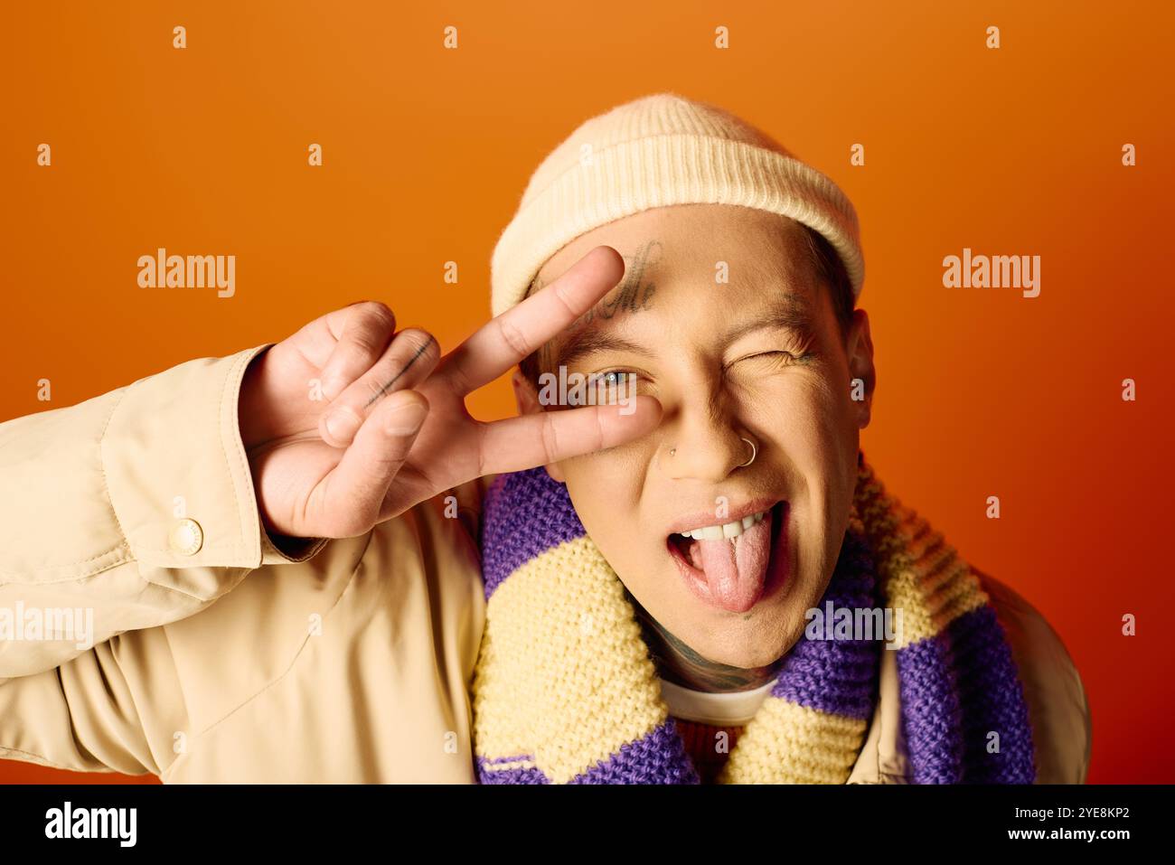 A tattooed young man playfully poses, sticking out his tongue and ...