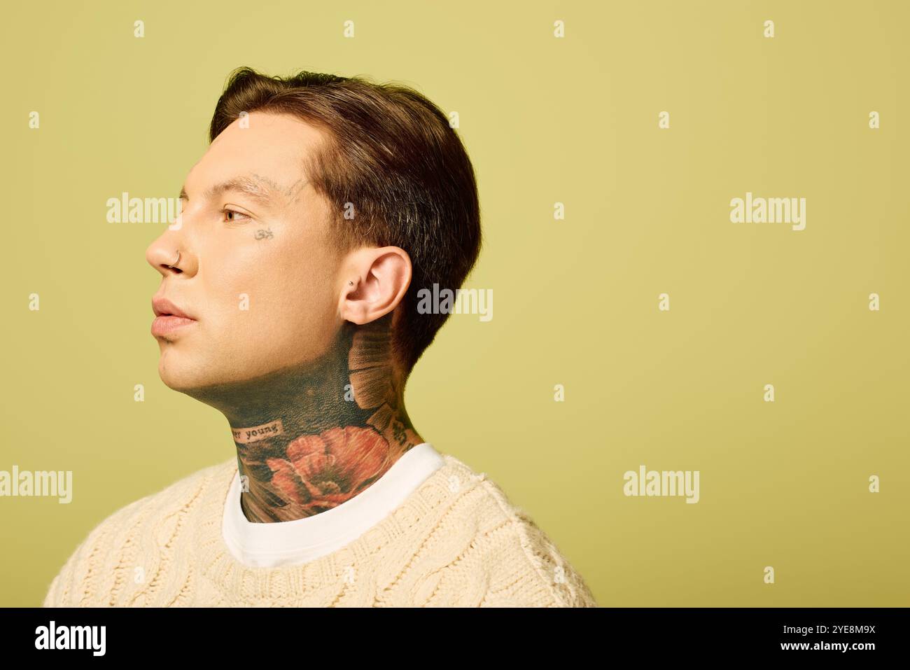 A young man with distinctive tattoos showcases his profile against a ...