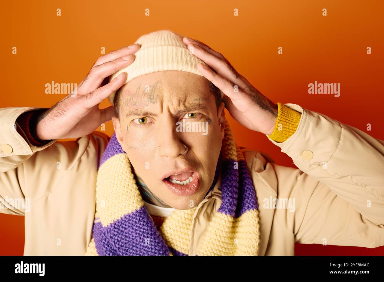 A young man with tattoos displays a look of shock while wearing a ...