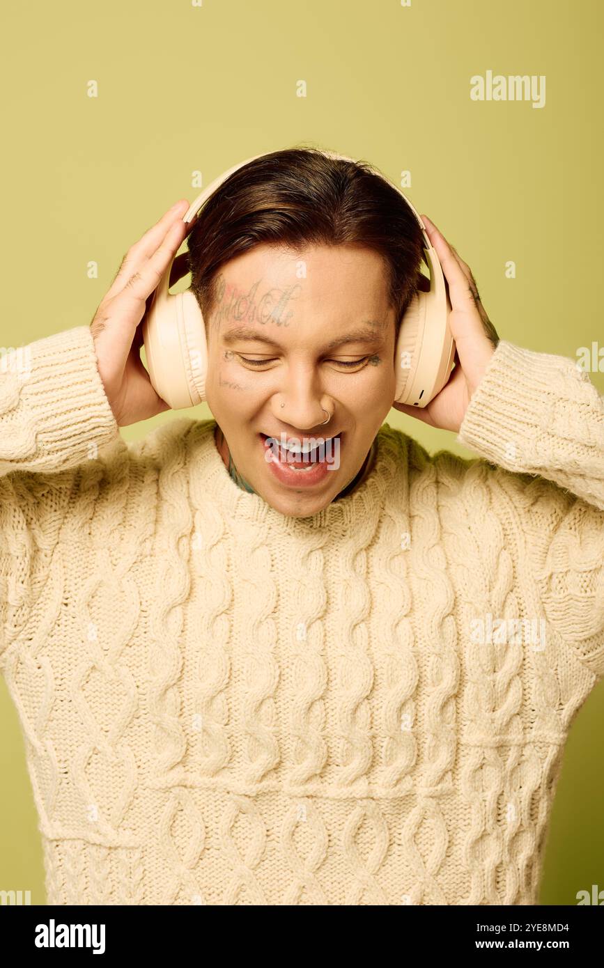 A young man with tattoos is enjoying music while wearing headphones ...
