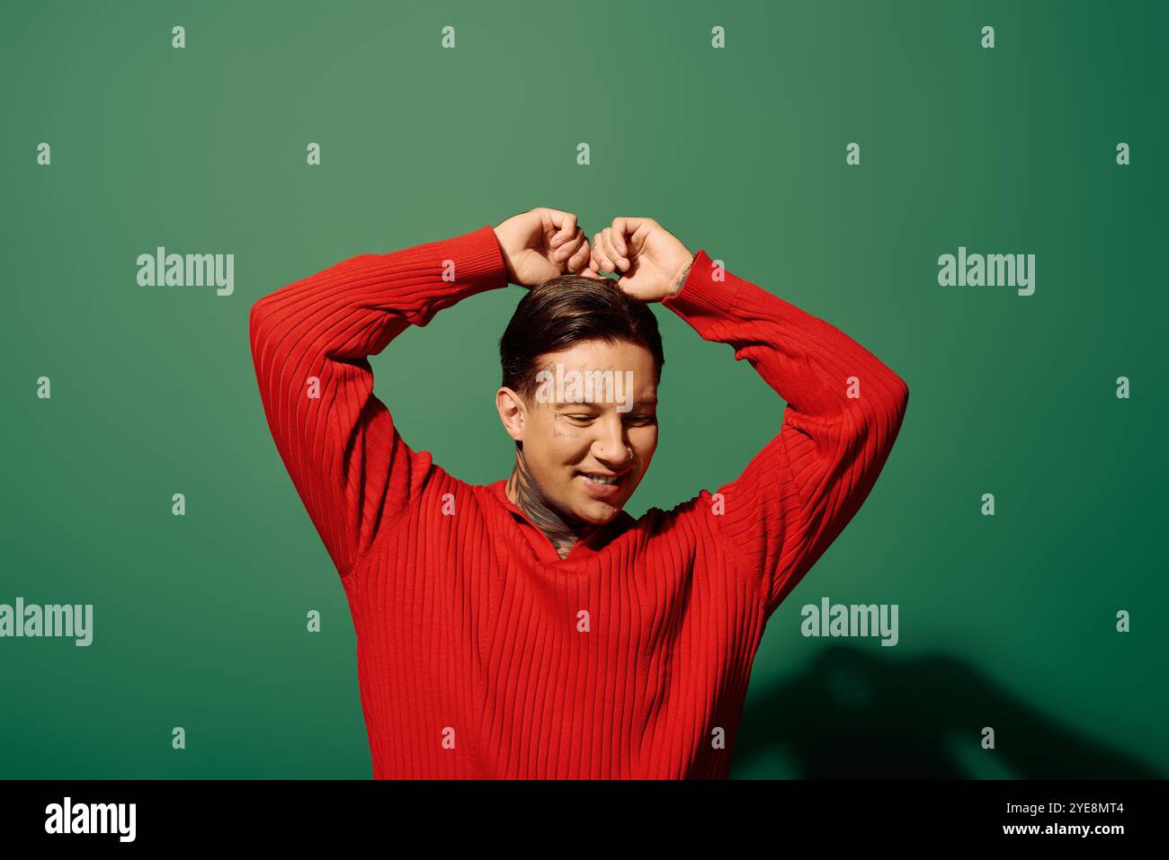 The young man smiles widely as he poses playfully with his hands raised ...