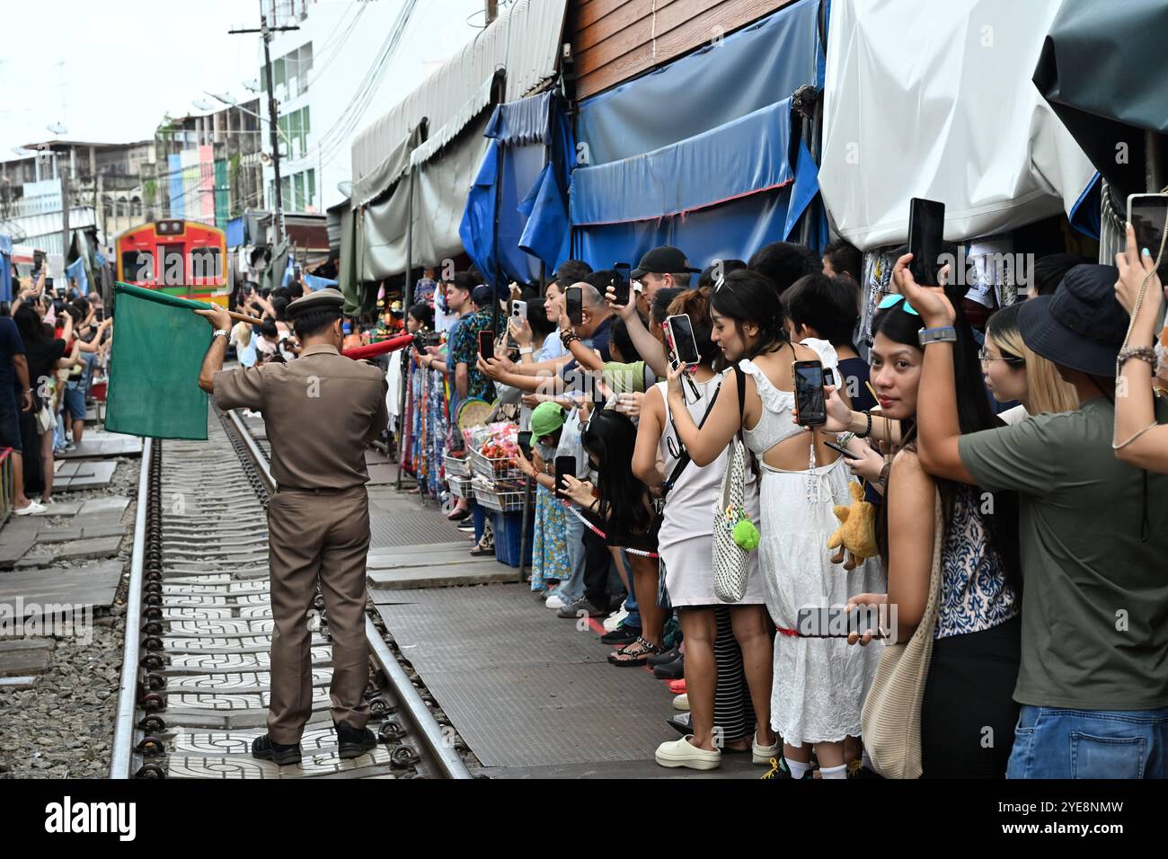 Railway market Thailand ,Station Master signals train by waving red and ...