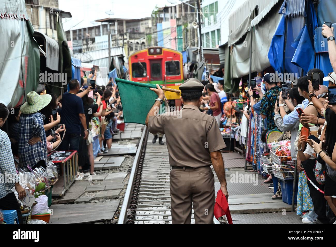 Railway market Thailand ,Station Master signals train by waving red and ...