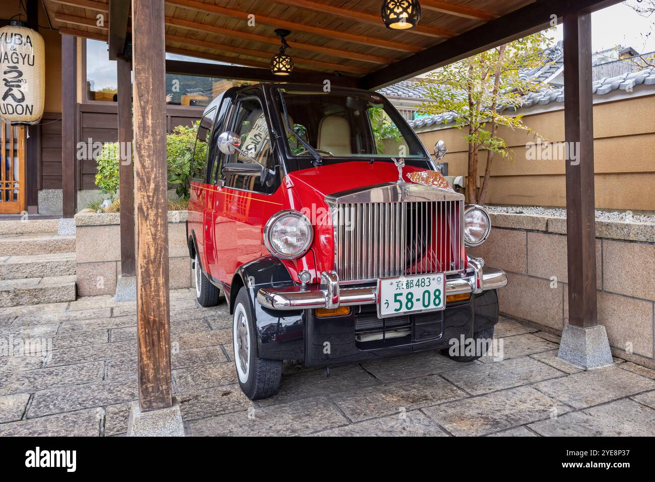 Small customised red car with Rolls Royce grill parked under lanterns ...