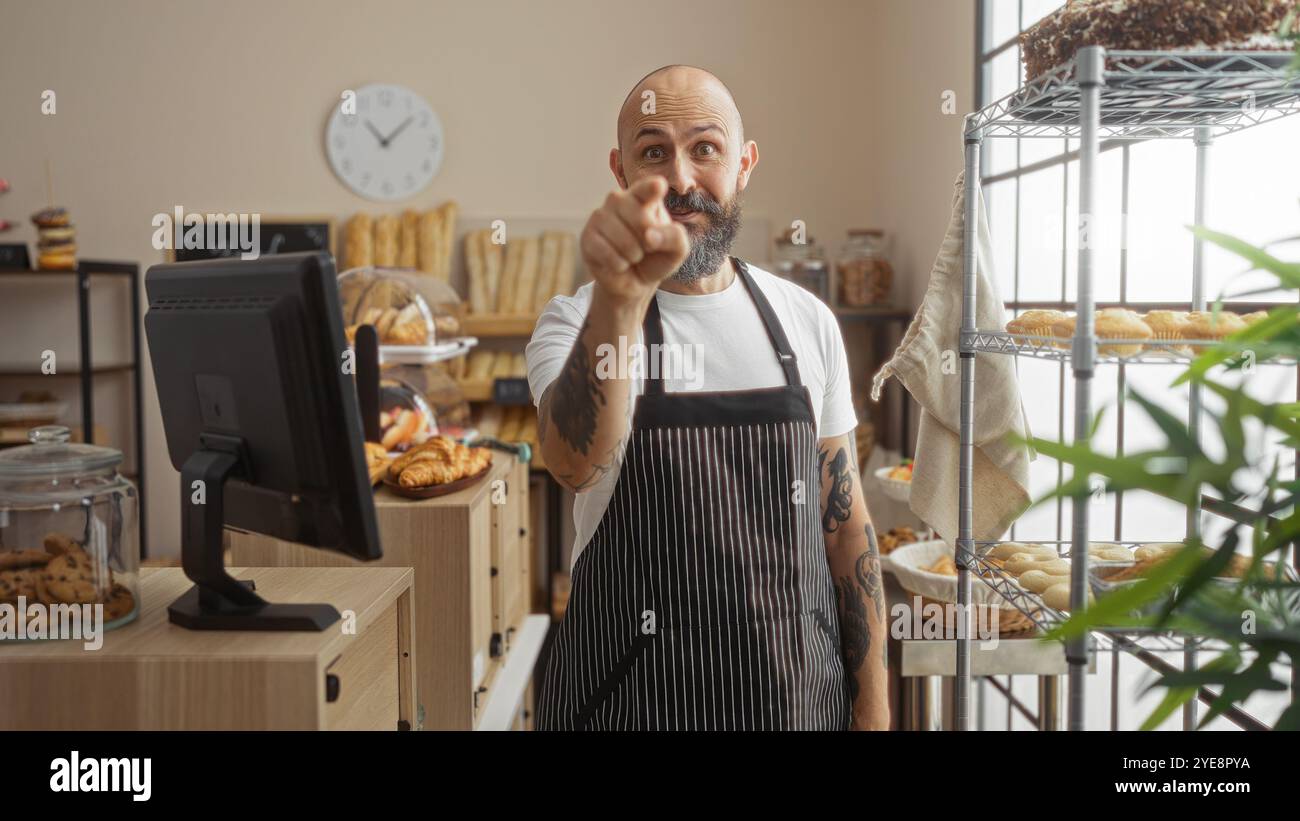 Hispanic man with a beard and bald head wearing an apron in a bakery ...