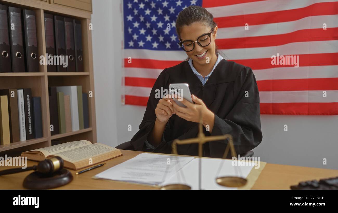 Young woman judge in courtroom using phone at desk with books and ...