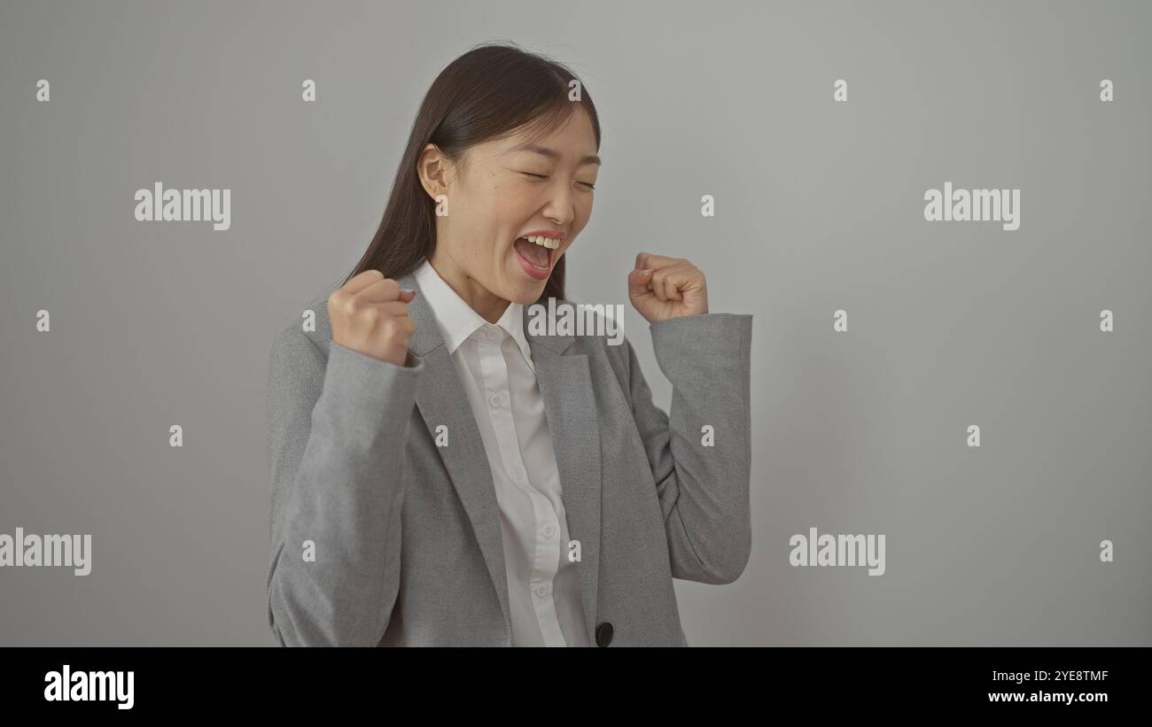 An exuberant chinese woman in business attire celebrates joyfully ...