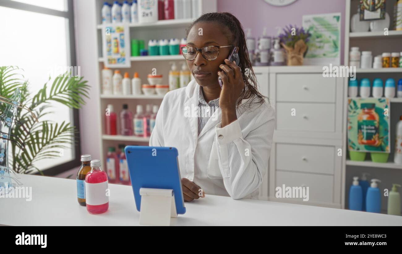 Female pharmacist speaking on phone while using tablet in pharmacy ...
