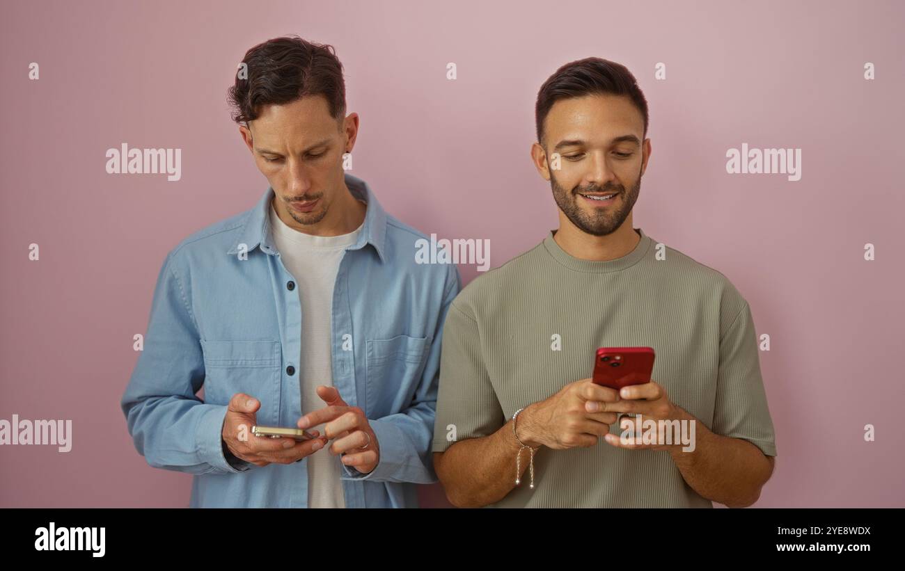 Men using mobile phones together against pink background conveying love ...