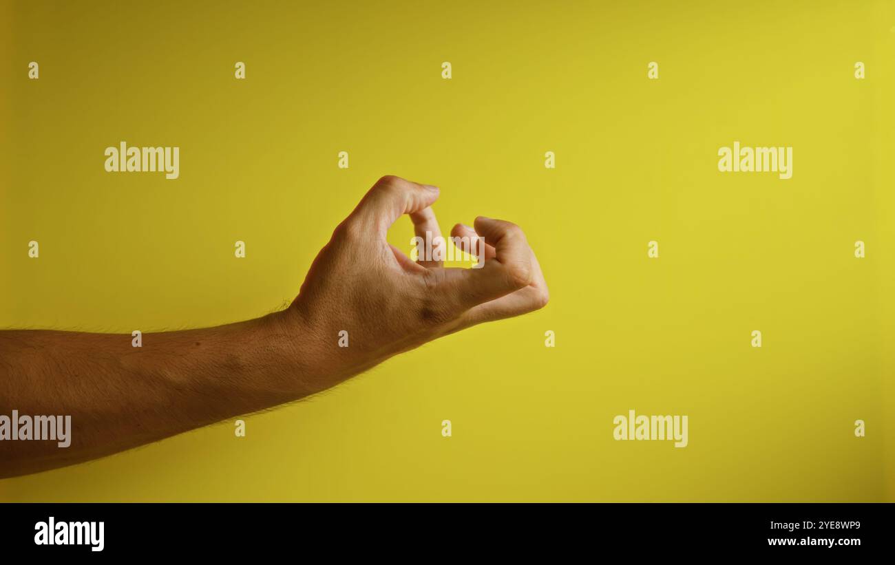 Man's hand forming an ok gesture against a vibrant yellow background ...