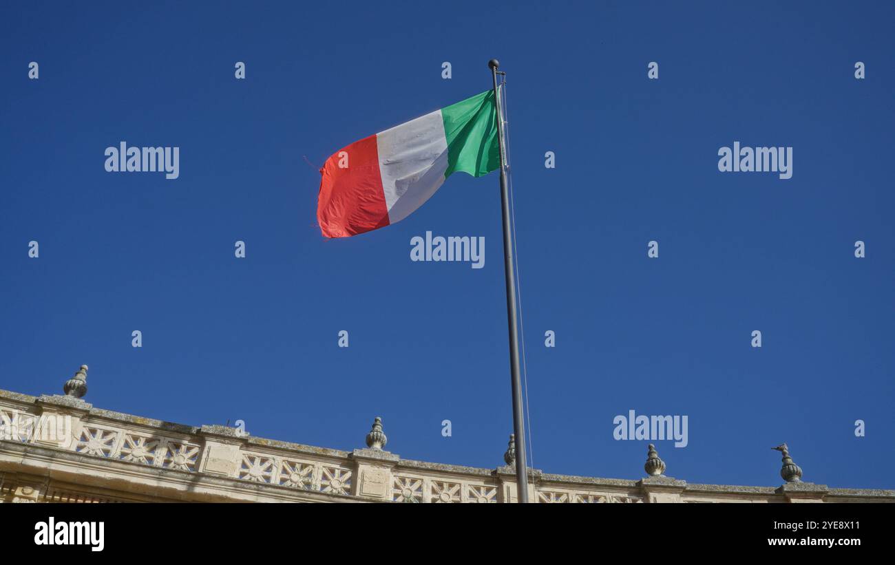 The italian flag flutters against a clear blue sky above a historic ...