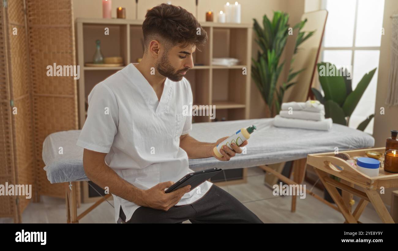 Handsome man in a spa room holding a skincare product and tablet ...