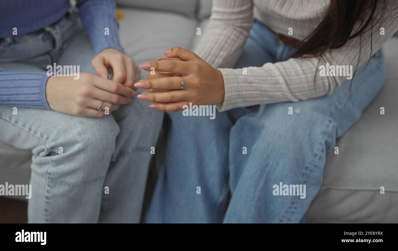 Two women holding hands, showcasing friendship and comfort in an indoor ...
