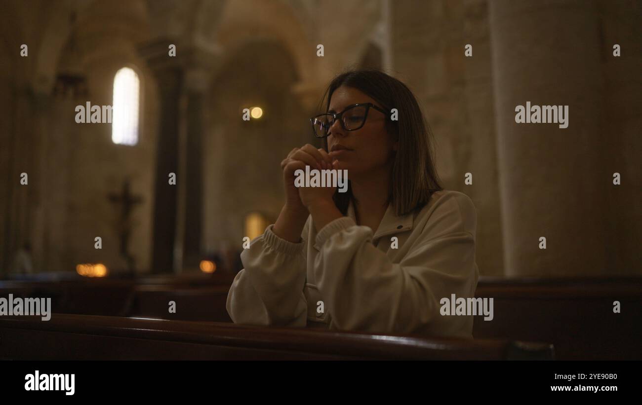 A beautiful young hispanic woman praying inside a christian church in ...