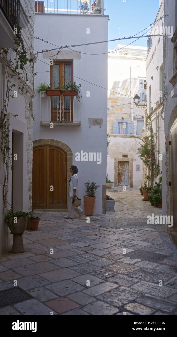 Young hispanic woman strolling through charming streets of polignano a ...