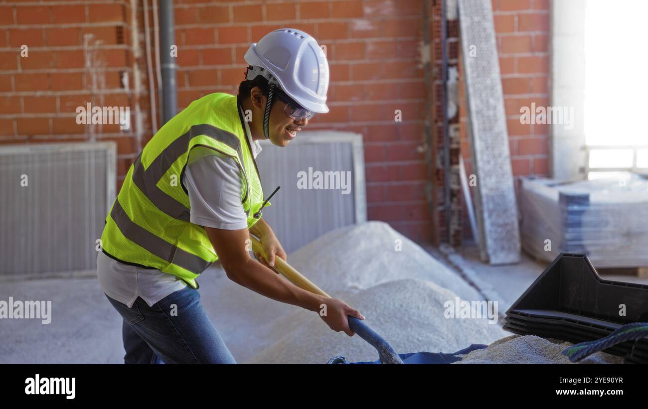 Young, chinese, man working indoors at a construction site, shoveling ...