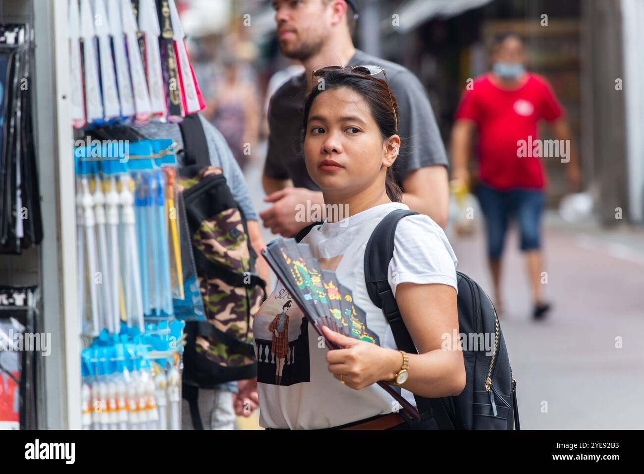Pretty Filipina woman tourist using hand fan to manually cool down her ...