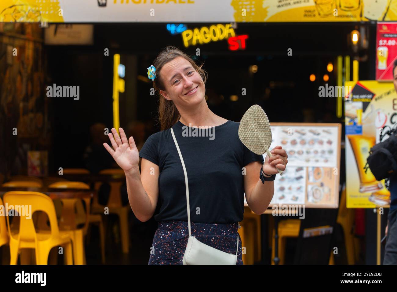 A friendly pretty caucasian woman holding a small size rattan fan ...
