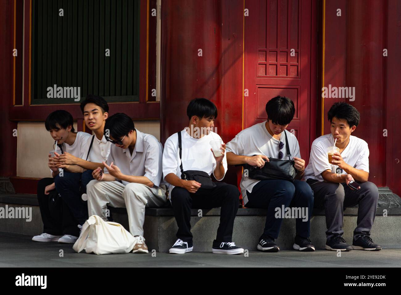 Tourists Japanese teenagers sit, rest and drink beverages, juice to ...