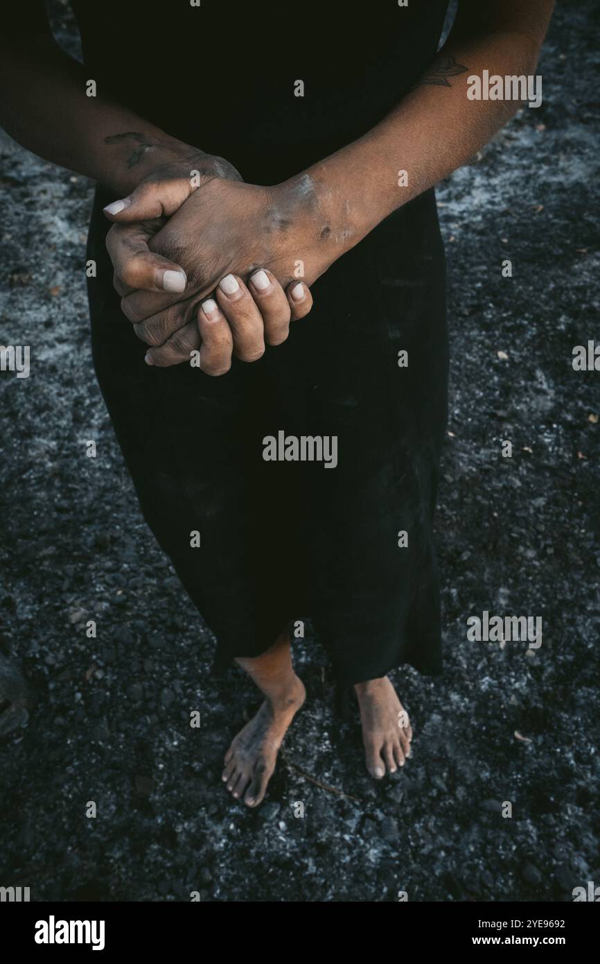 Hands clasped over ashy ground Stock Photo - Alamy