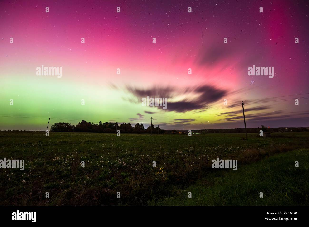 A captivating view of a rural field under a vivid aurora, with green ...