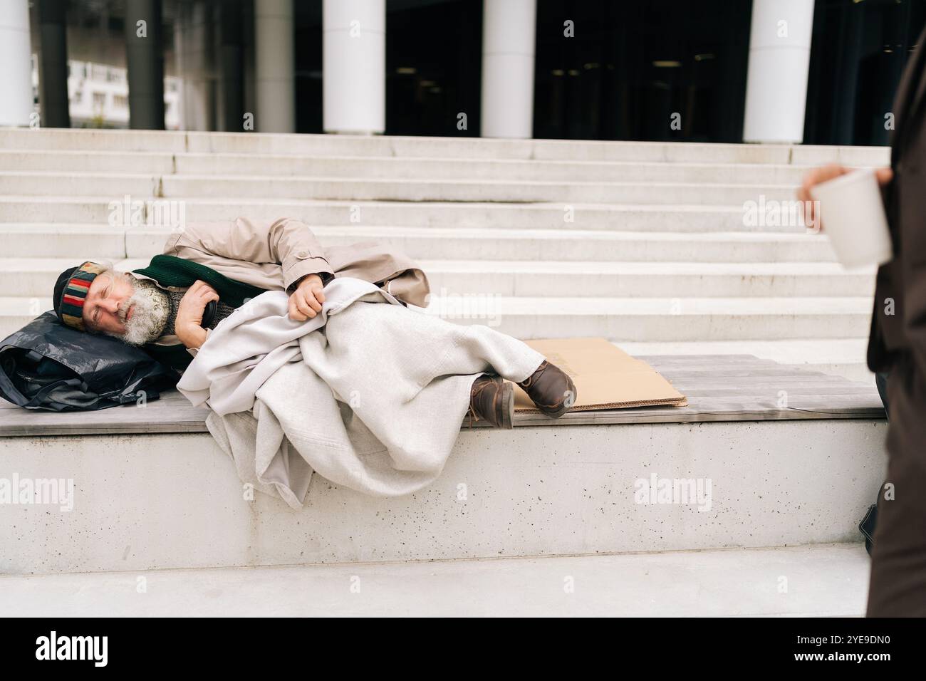 Senior homeless man lying sleeping on street covered with blanket on ...