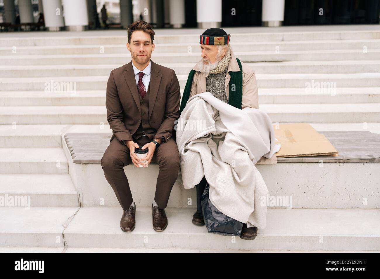 Portrait of young businessman in suit holding cup of coffee and sitting ...