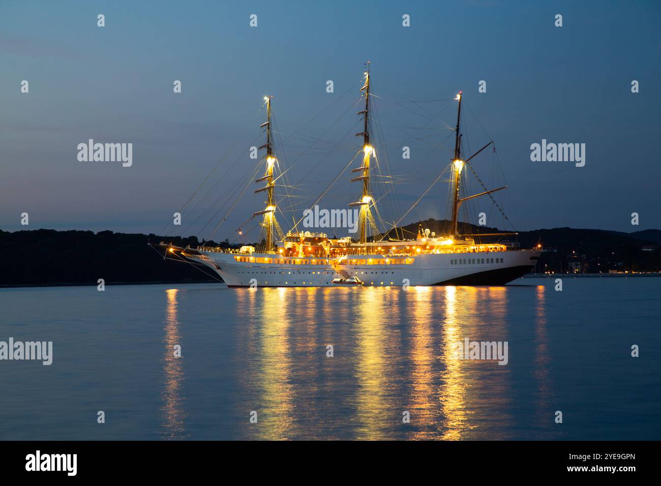 Sailing ship illuminated with lights at dusk in a harbour; Rovinj ...