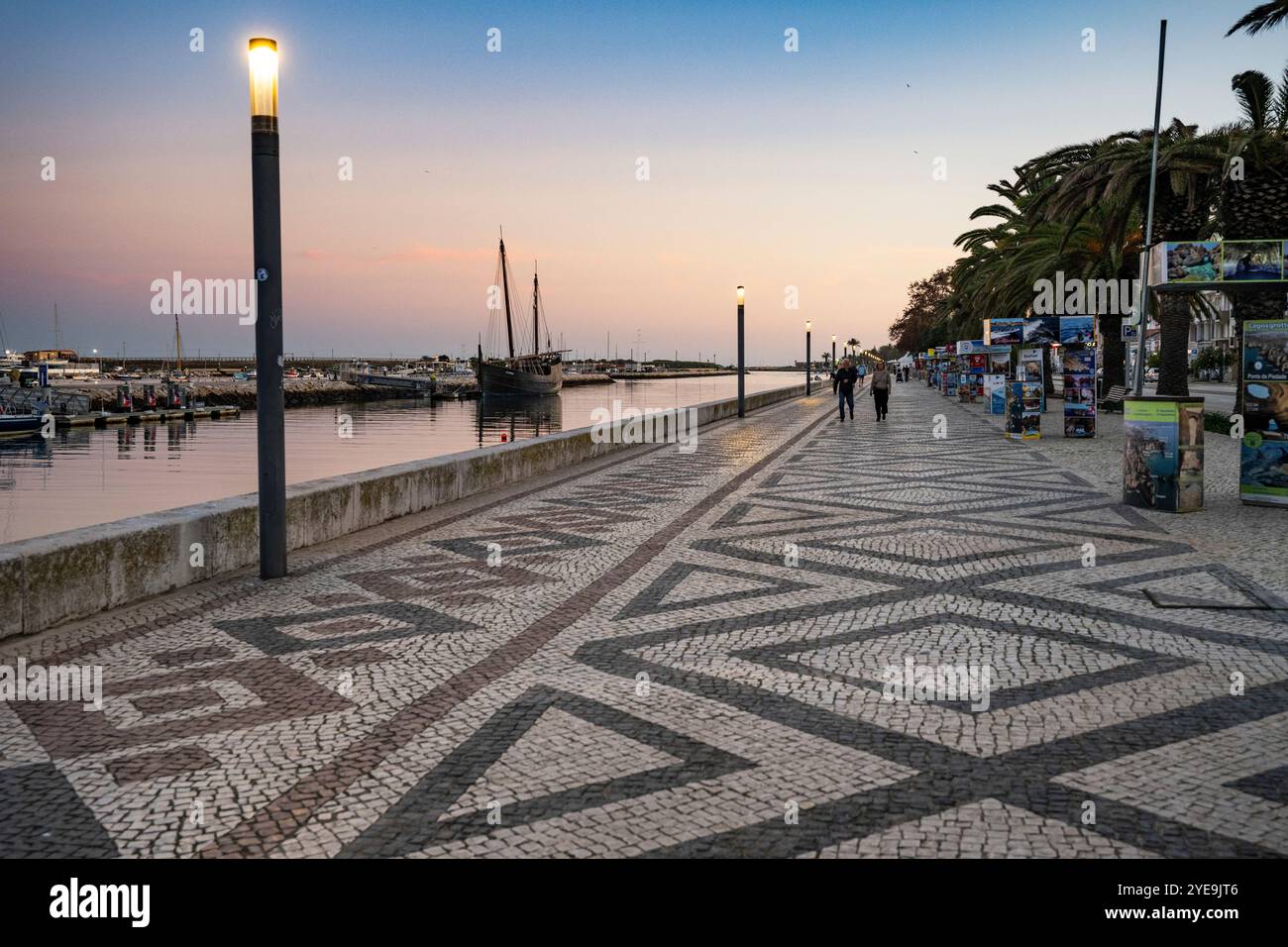 Promenade along the harbour of the coastal town of Lagos at twilight ...