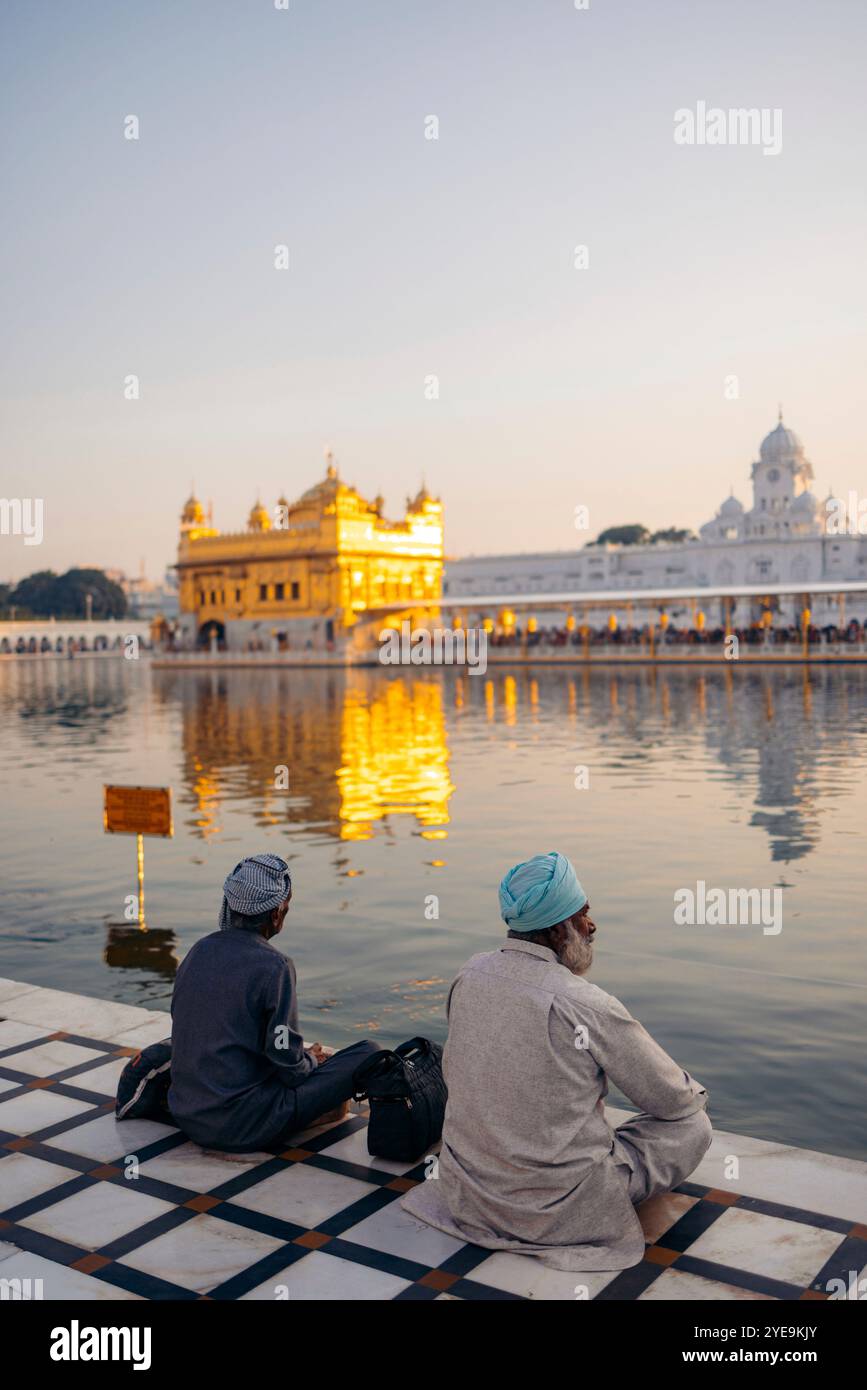 Men sit at the water's edge of a pool of the Golden Temple, a Sikh ...