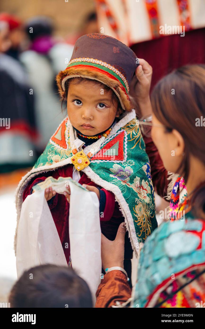 Young child dressed in traditional buddhist clothing stands looking at ...