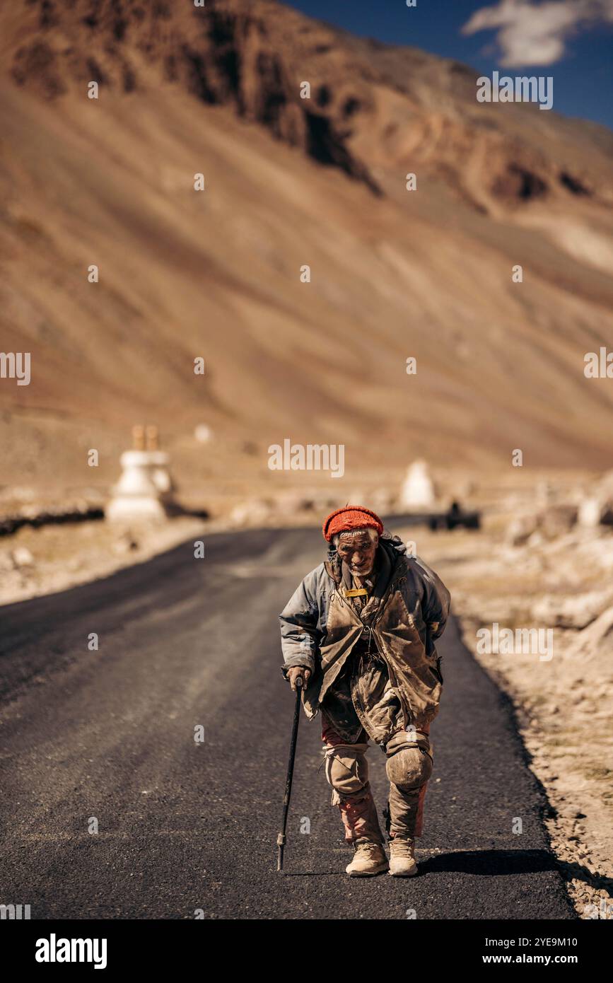 Senior man walks with a cane on an asphalt road, near Kurgiakh in ...