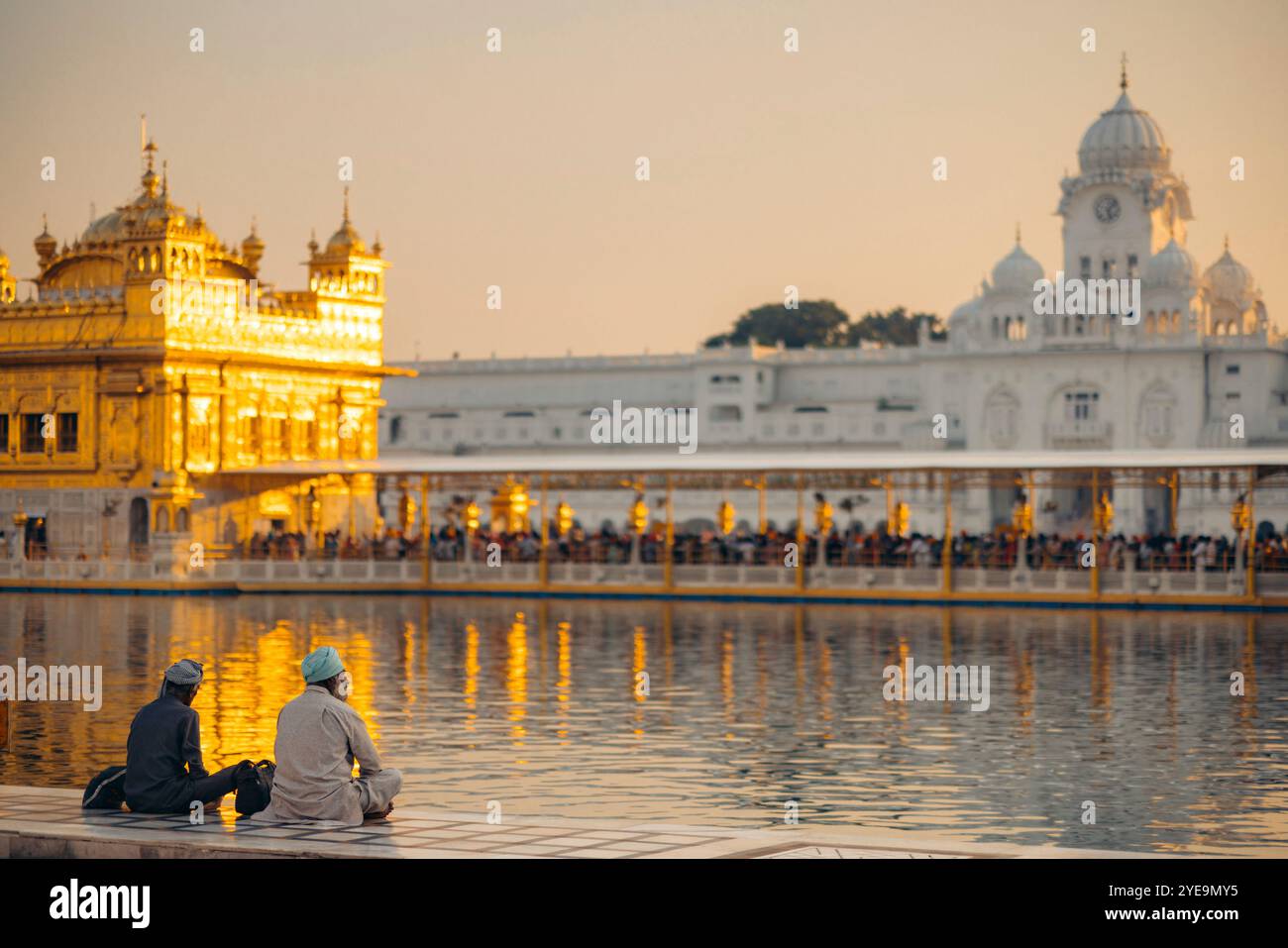 Men sit at the water's edge of a pool of the Golden Temple, a Sikh ...