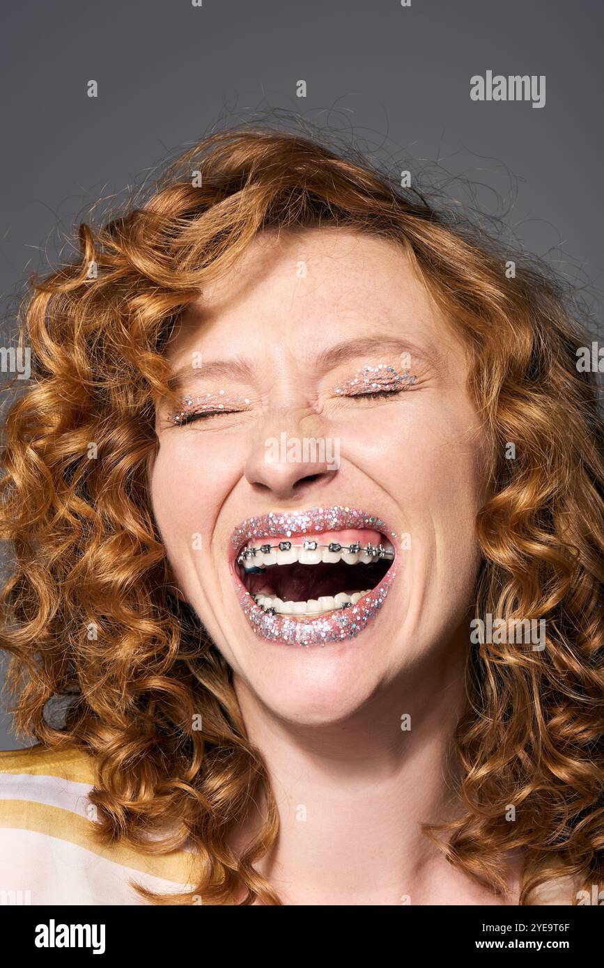 A young woman with curly hair joyfully posing cheerfully, showing off ...