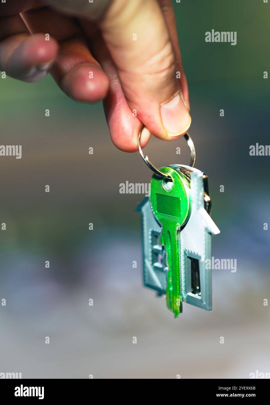 hand grips a vibrant green key attached to a silver keychain shaped ...