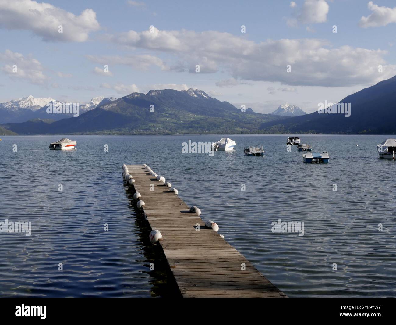 wooden jetty in annecy lake, alpine lake with boats surrounded by ...