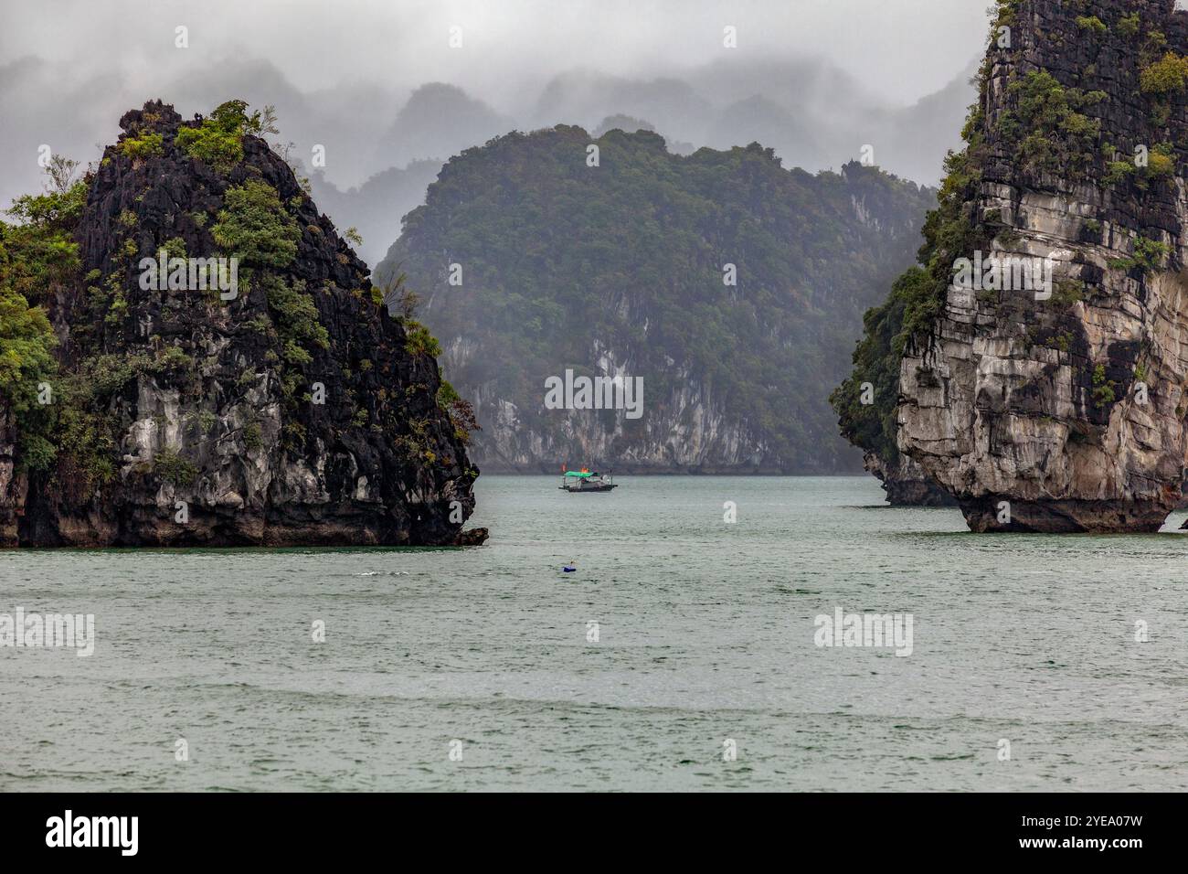 Lone boat between karst rock formations at Ha Long Bay in Vietnam ...