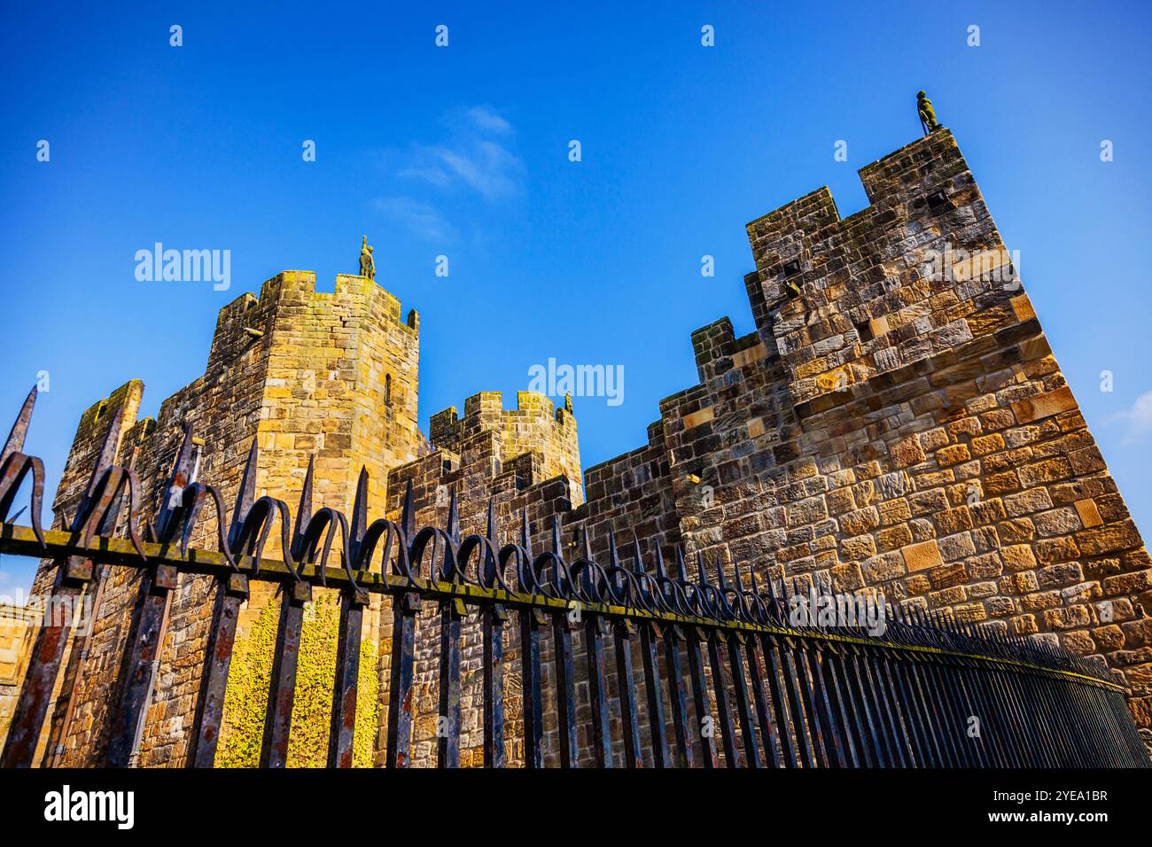 Fence outside Alnwick Castle and the stone wall facade with sculptures ...