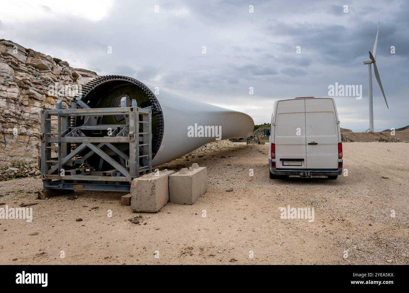 A rotor blade of a wind turbine on the ground along side a van, showing ...