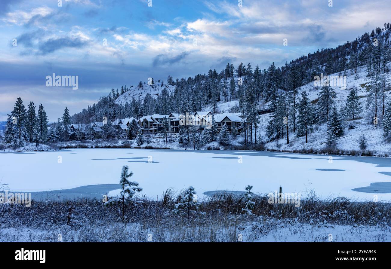 Housing development by a snow-covered frozen lake in winter; Kelowna ...