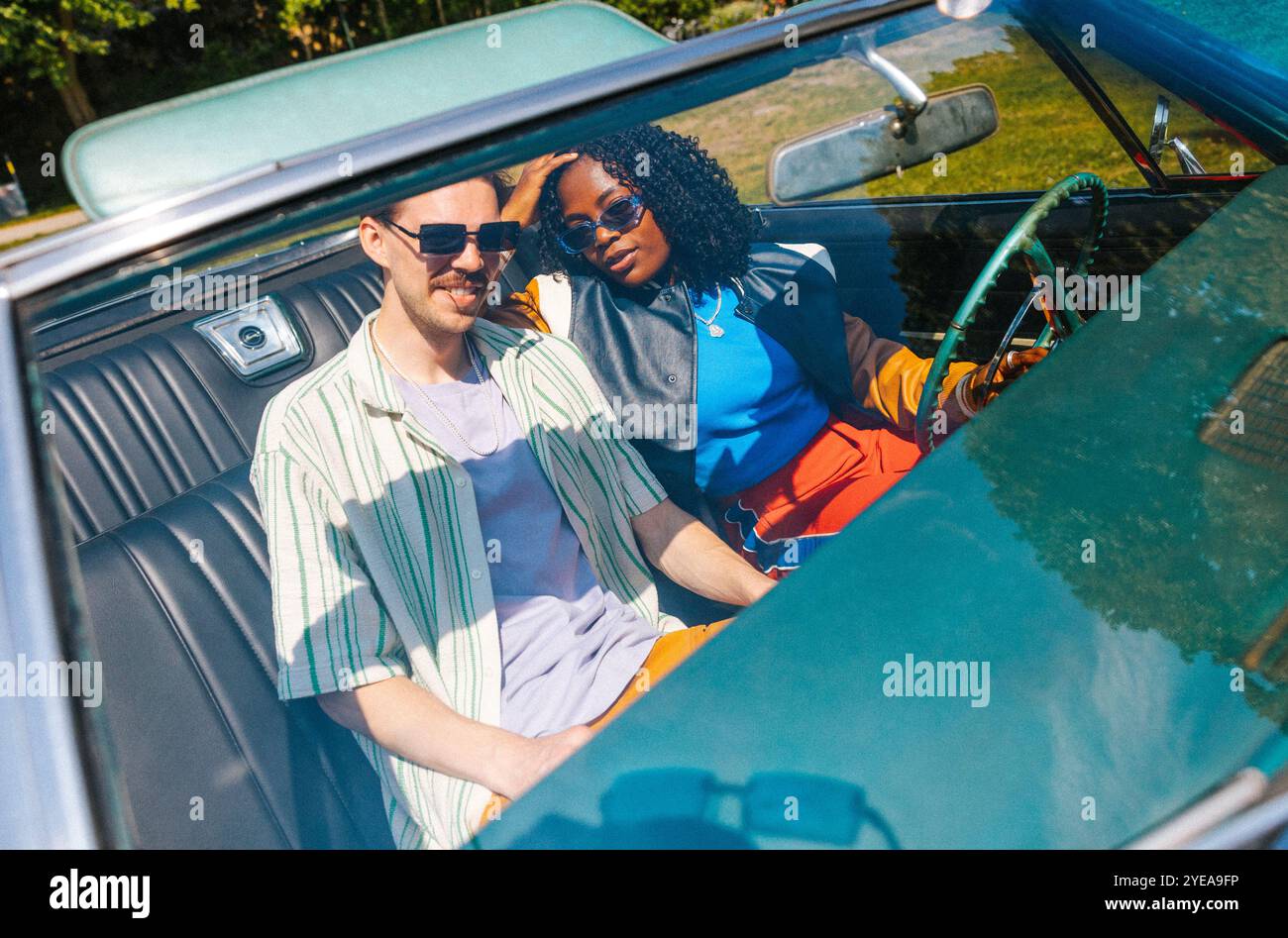 High angle portrait of male and female friends sitting in vintage car ...