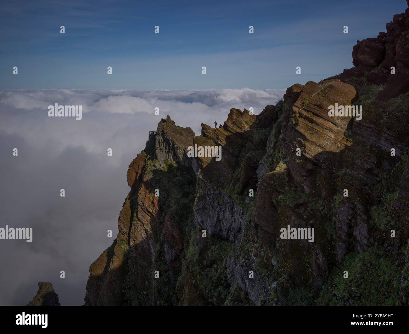 Lone hiker stands looking out along a peaked ridge on Pico do Areeiro ...