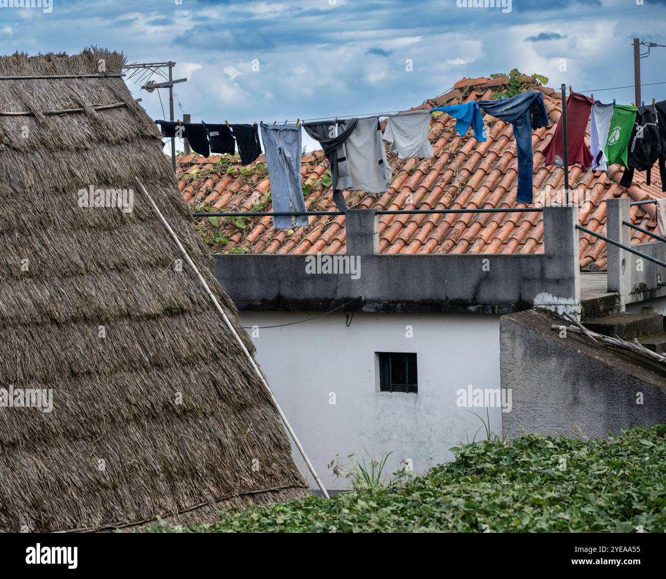Clothesline between houses, roofs with clay roof tiles and thatching ...