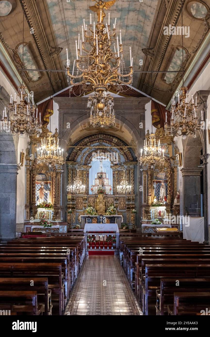 Interior of a church with ornate altar and chandeliers, a center aisle ...