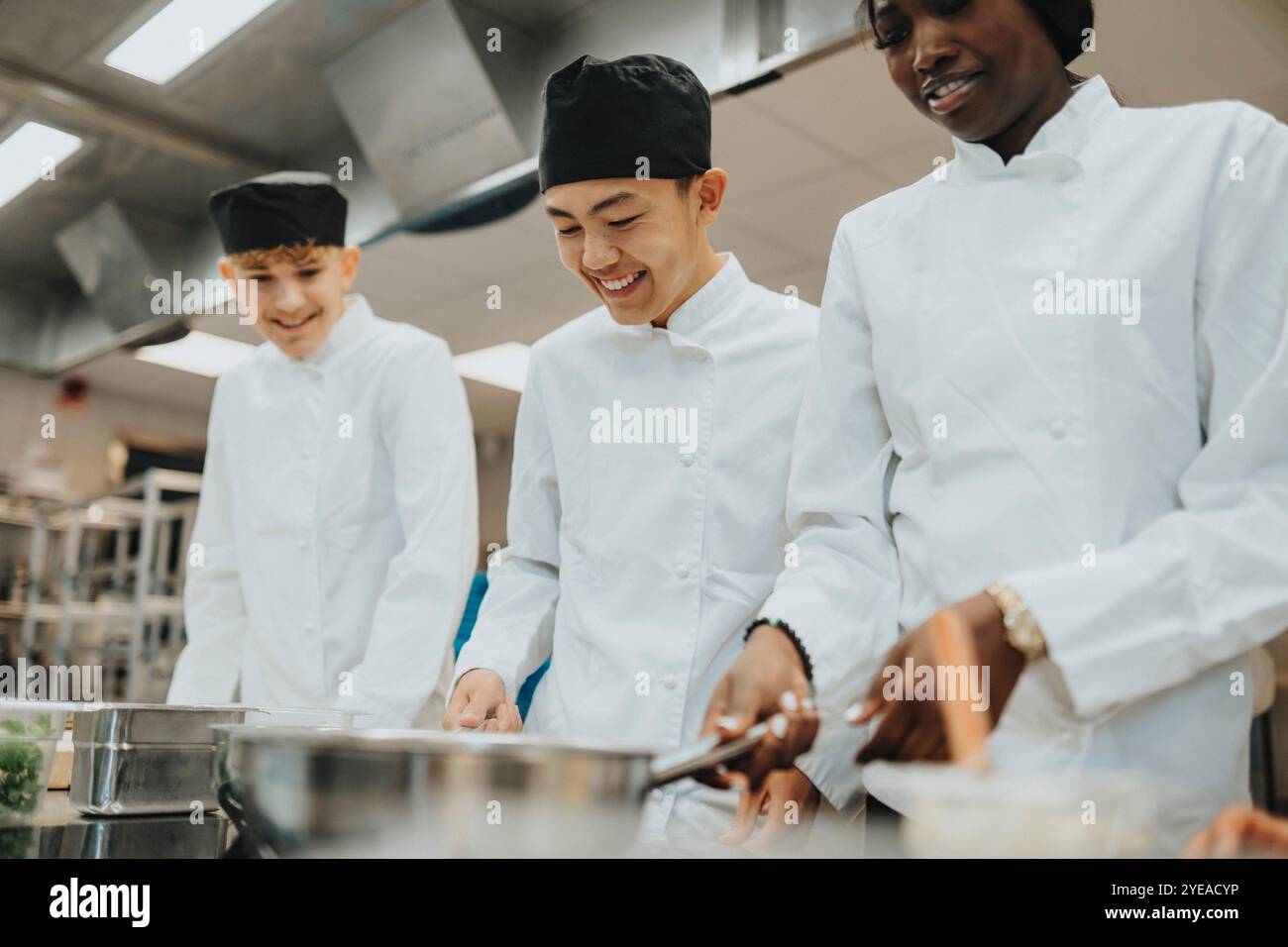 Smiling male and female trainee cooking food while working in ...