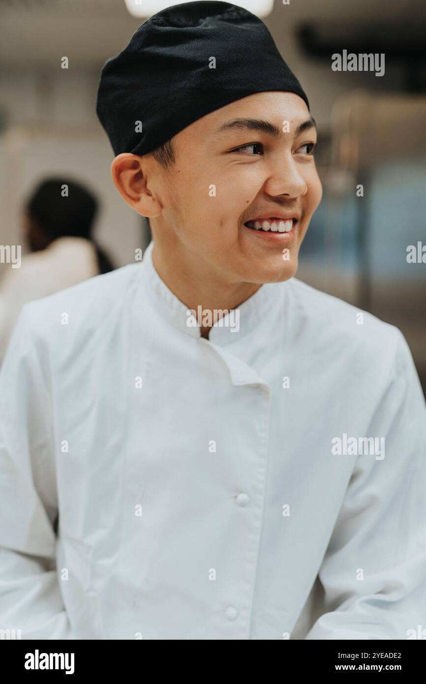 Happy male teenage trainee wearing chef's hat at culinary school Stock ...