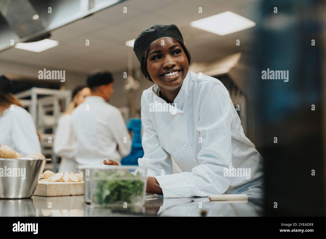 Happy female trainee leaning on kitchen counter Stock Photo - Alamy