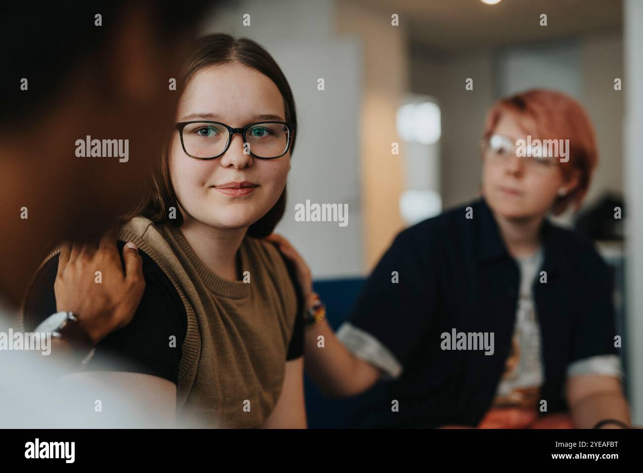 Teenage girl being console by male and non-binary friend during group ...