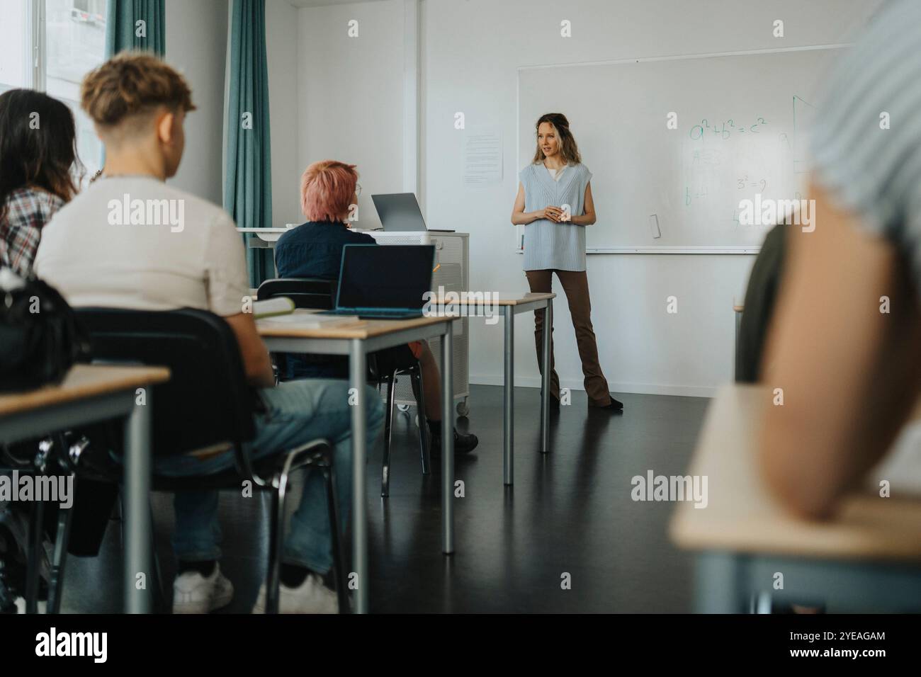 Teacher discussing with male and female students while standing against ...